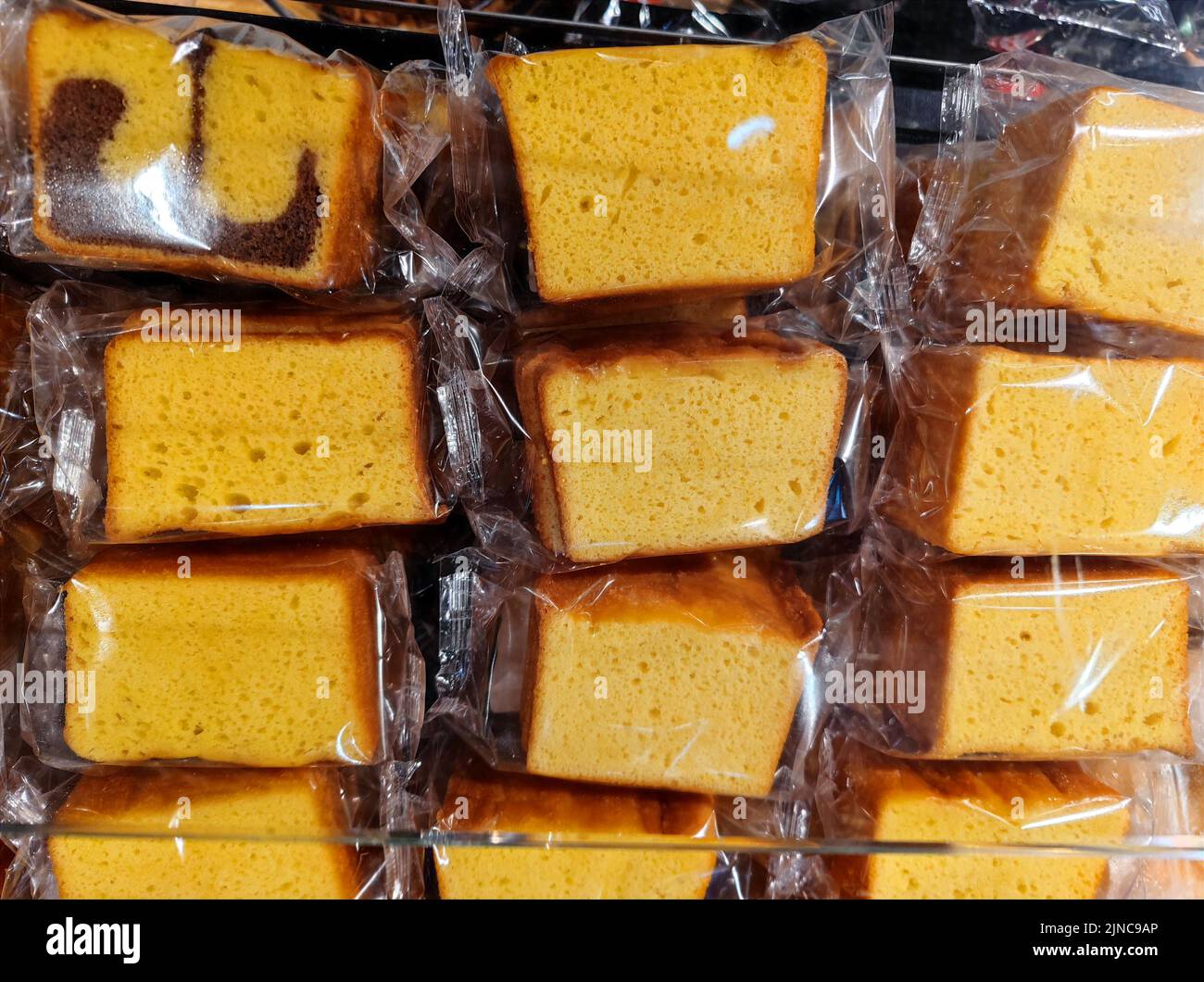 Delicious rows of cake and muffins on a counter shelf in a supermarket ...