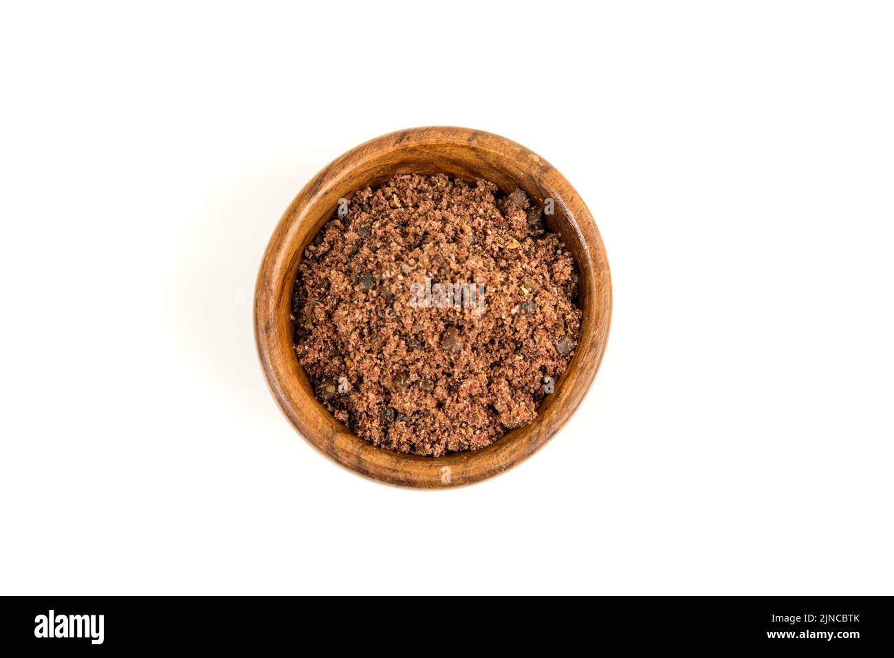 Ground dried sumac berry powder in a small wood bowl over white top ...