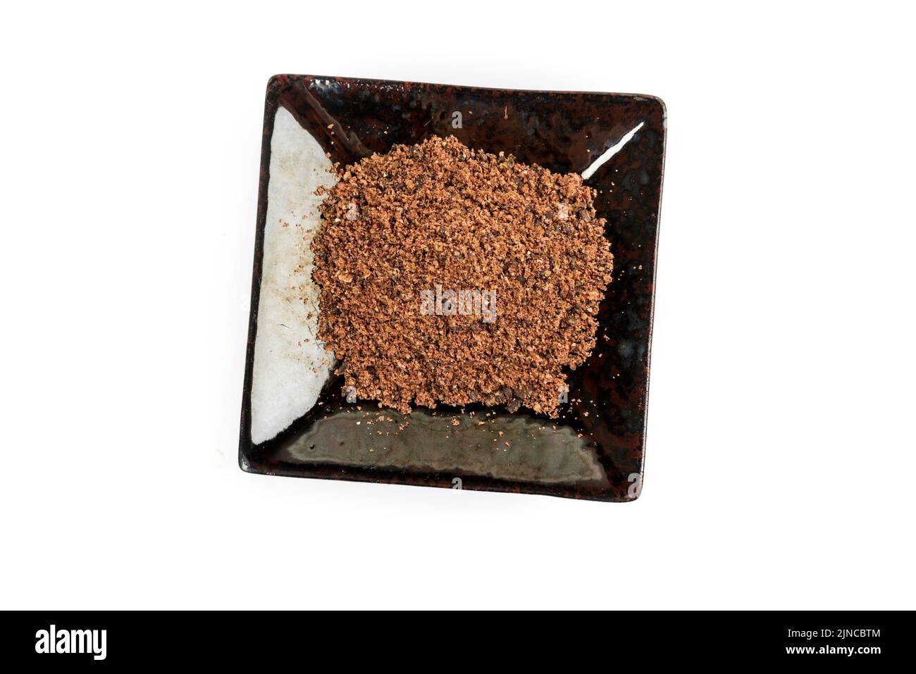 Ground dried sumac berry powder in a black ceramic plate top down Stock ...