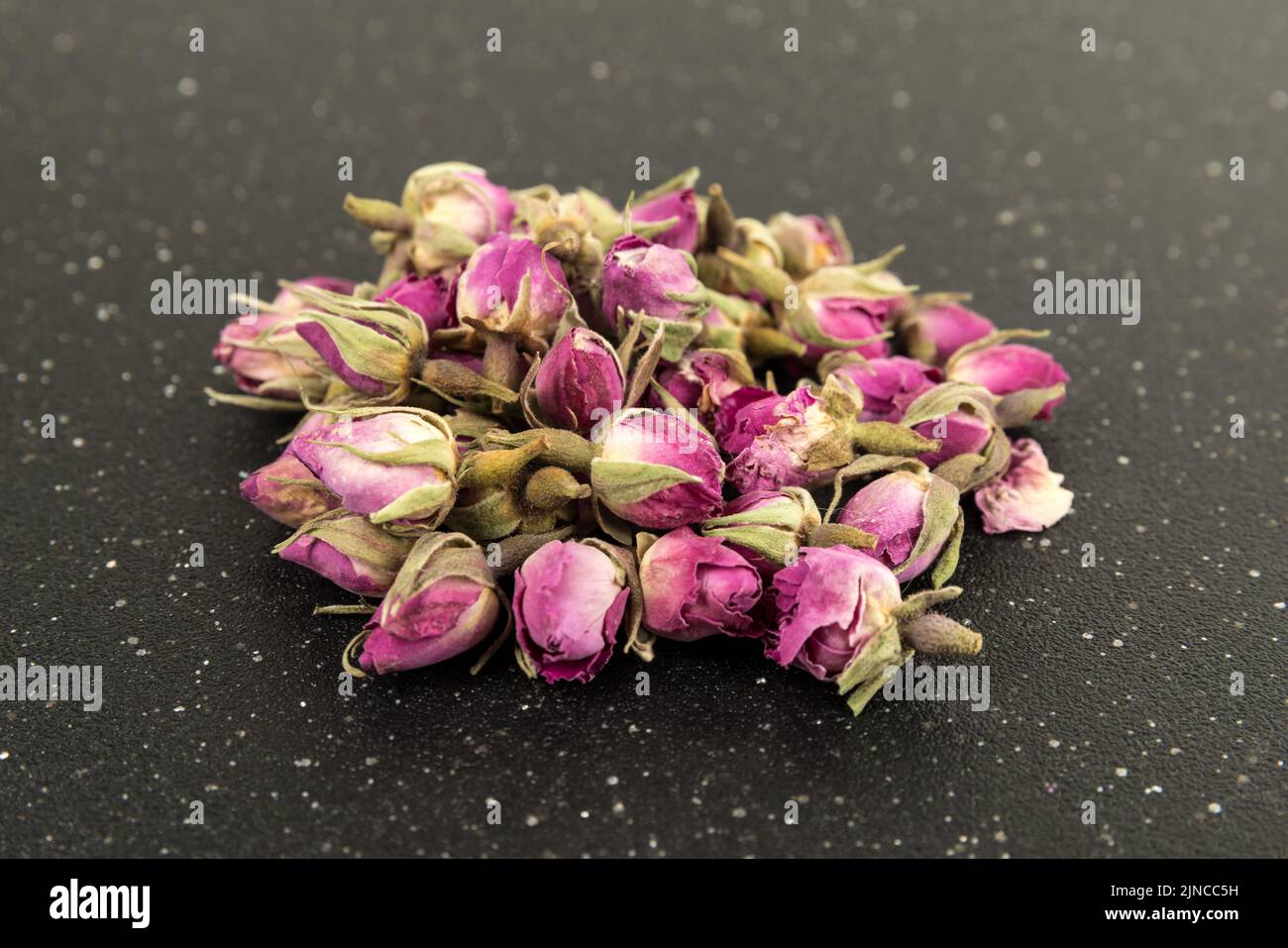 Dehydrated pink rose buds on a black cutting board Stock Photo - Alamy