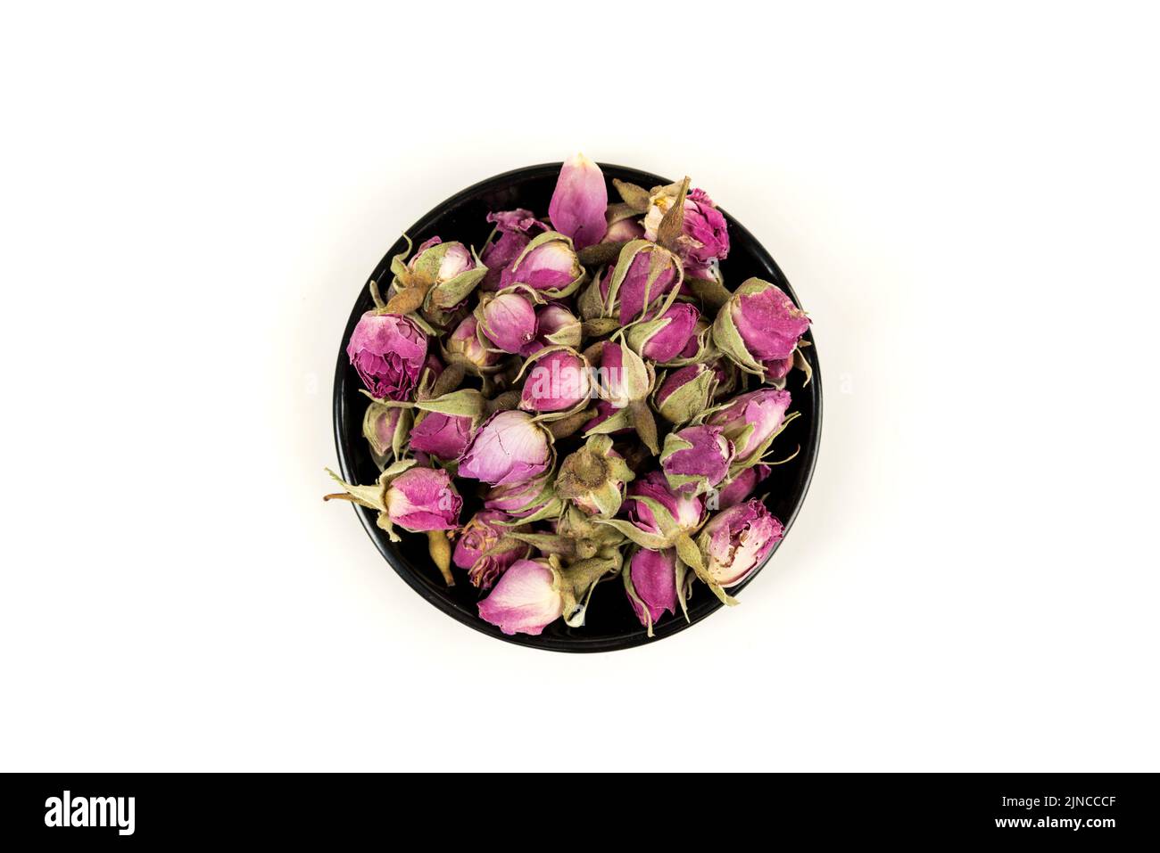 Dehydrated pink rose buds in a black bowl top down view isolated over ...
