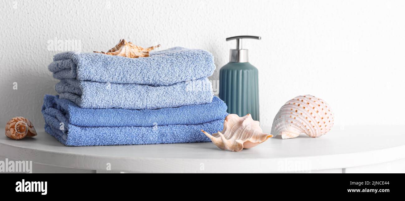 Stack of clean towels, sea shells and soap on table in bathroom Stock ...