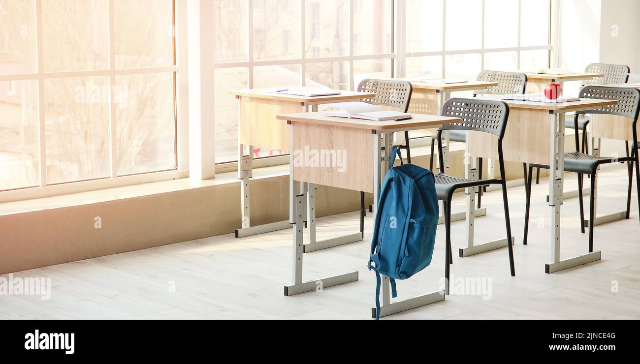 Interior of modern empty classroom with hanging backpack on desk Stock ...