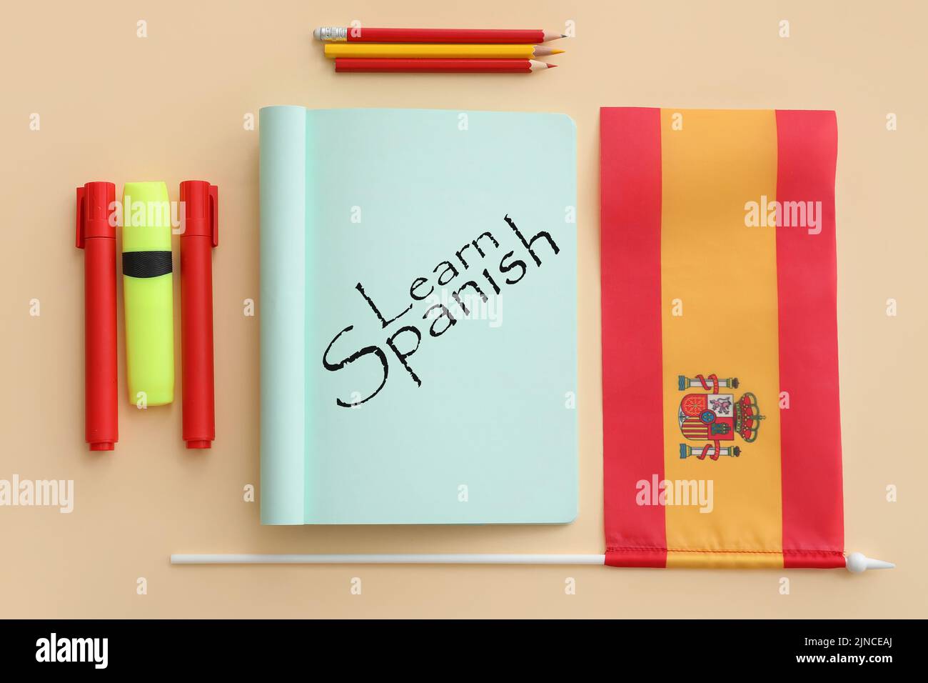 Notebook with text LEARN SPANISH, flag of Spain and stationery on beige ...