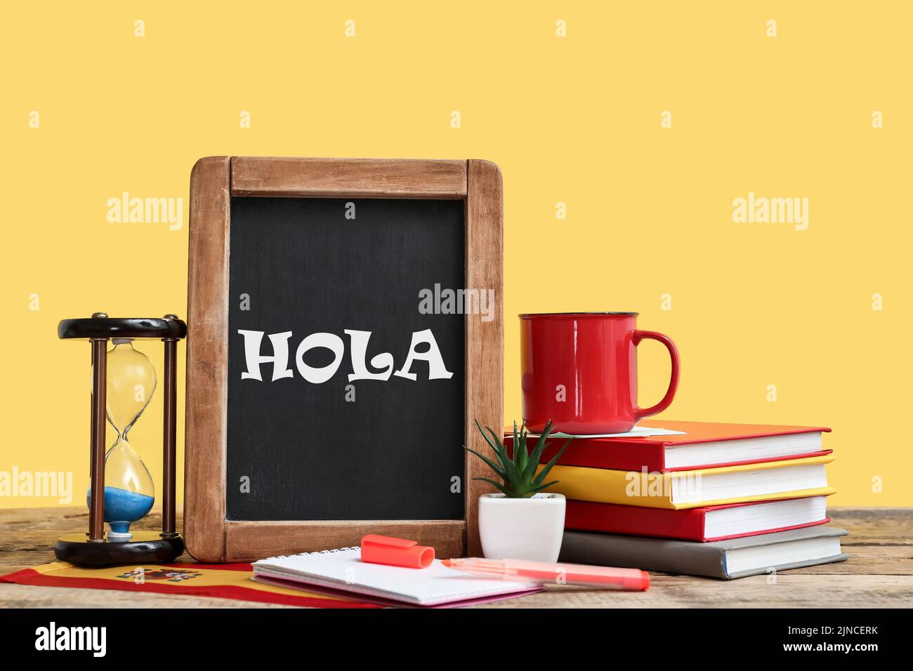 Chalkboard with text HOLA (HELLO). hourglass and stationery on table ...