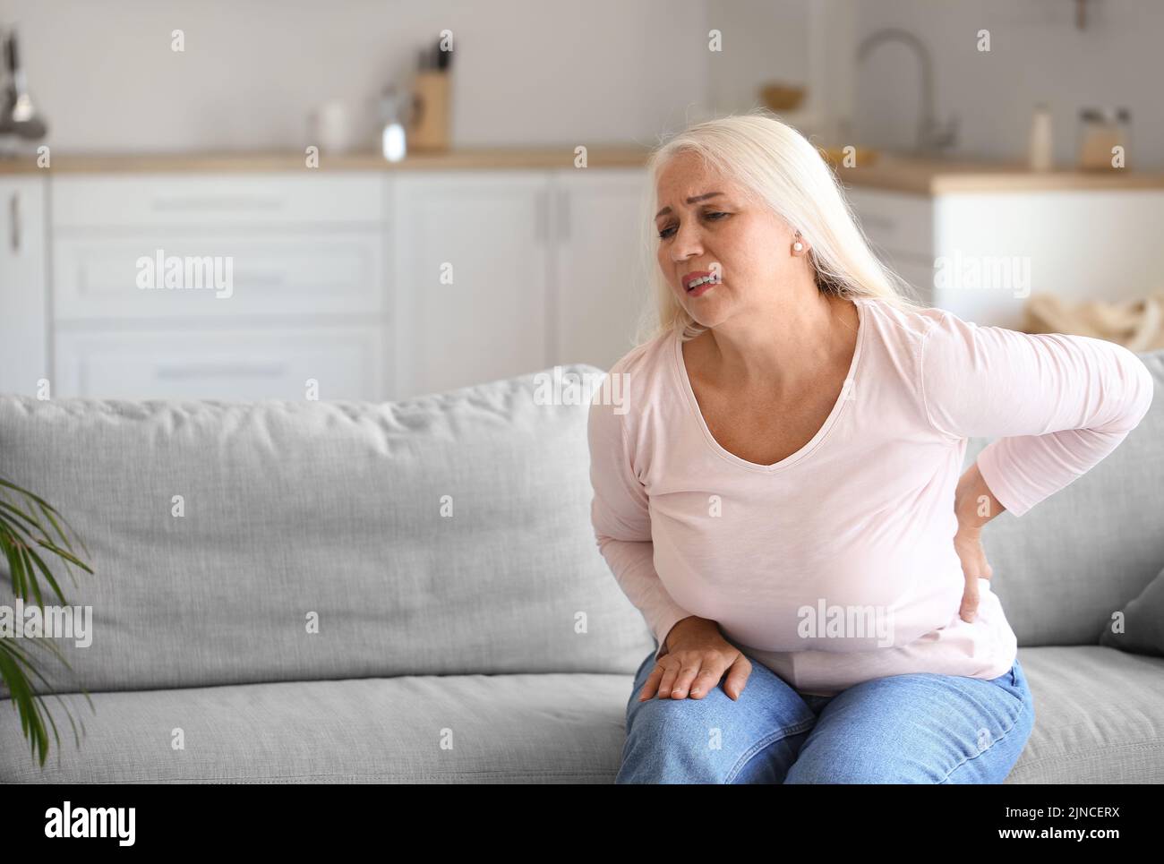 Mature woman suffering from back pain in kitchen Stock Photo - Alamy