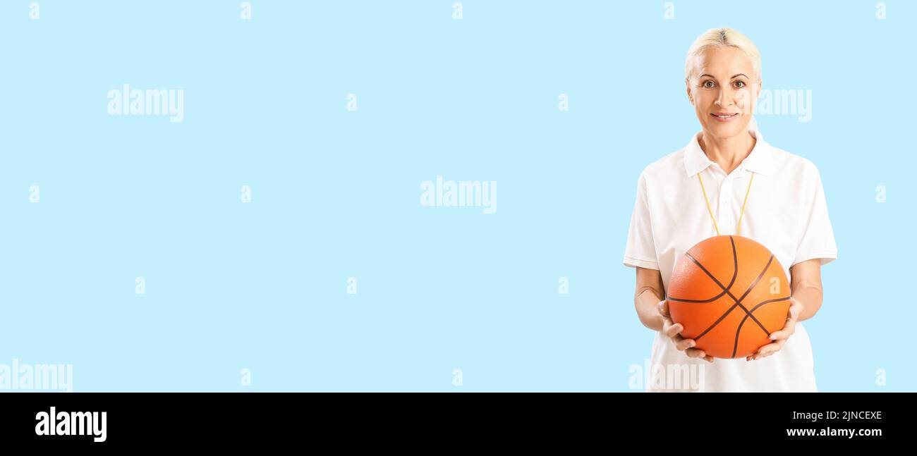 Mature PE teacher with ball on light blue background with space for ...