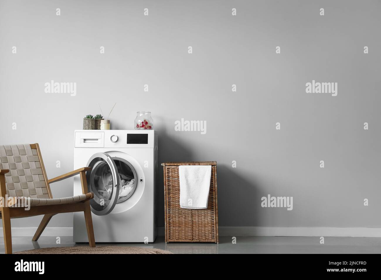 Interior of modern laundry room with washing machine, armchair and ...