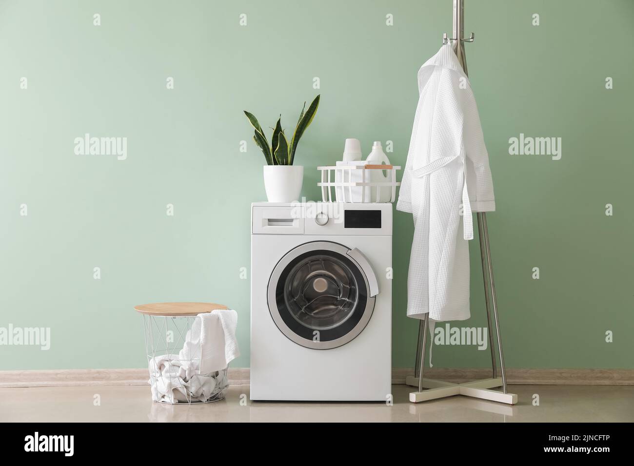 Interior of stylish laundry room with washing machine, rack and ...
