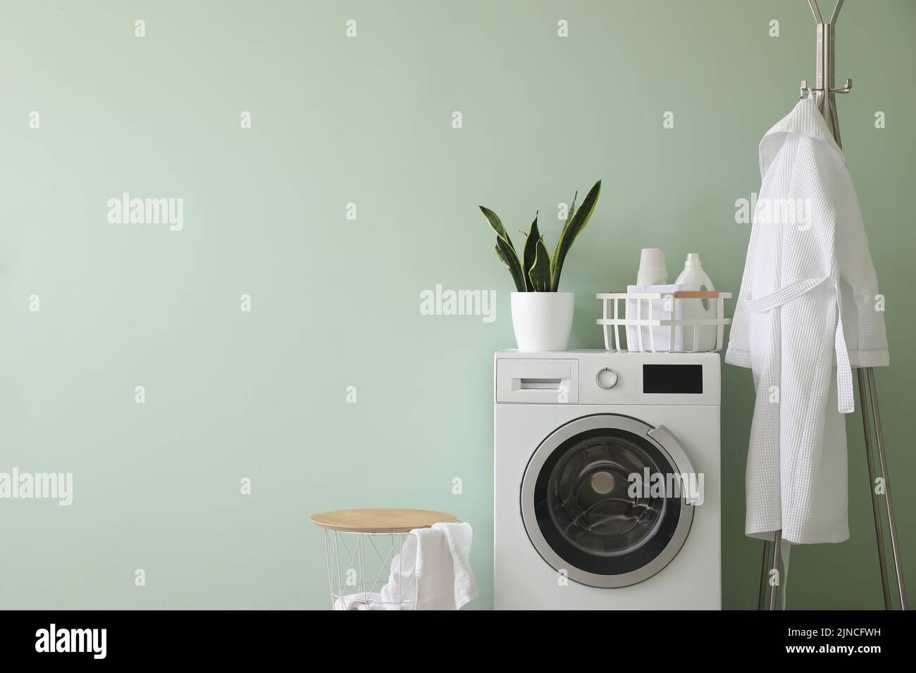 Interior of stylish laundry room with washing machine, rack and ...