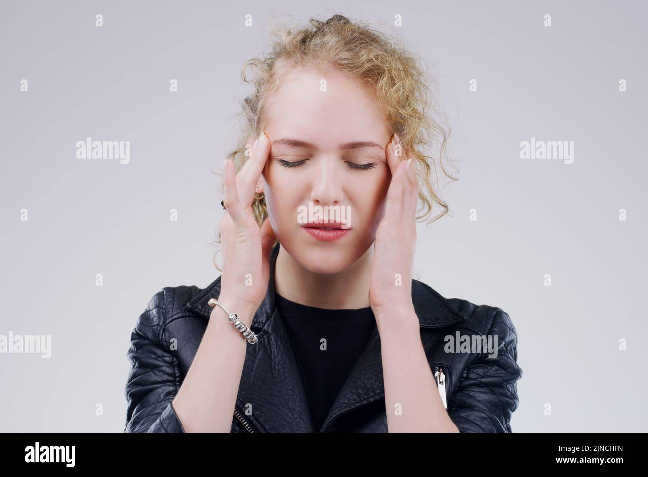 Why did this headache have to start now. a young woman holding her head ...