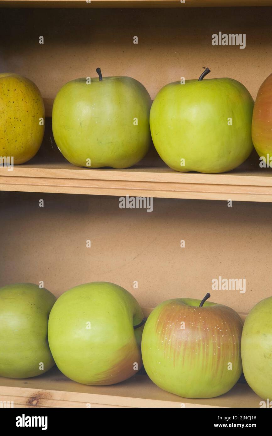Close-up of green apples for sale displayed on wooden shelves behind a ...