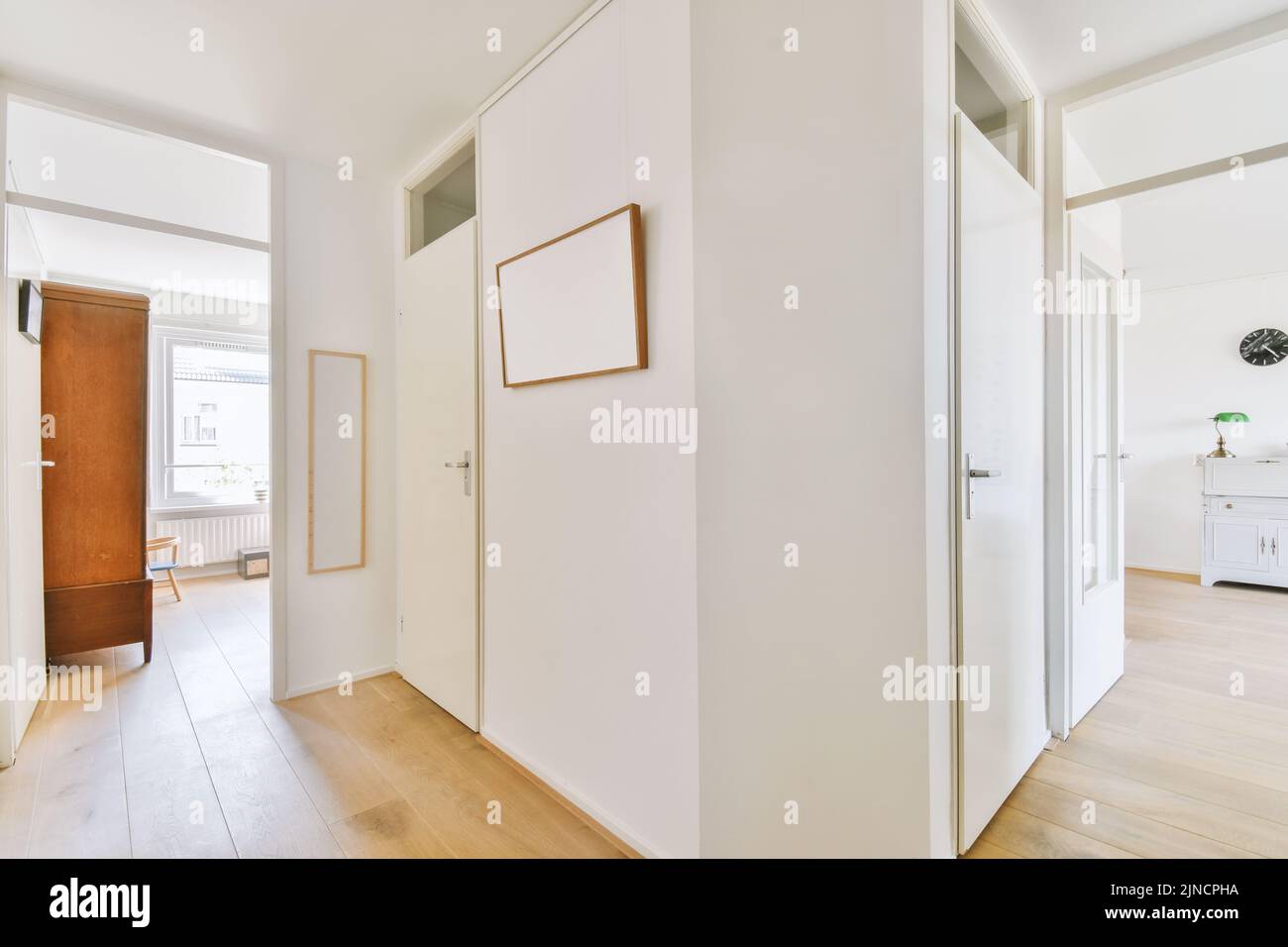 Narrow corridor with white walls and doors leading to spacious room ...