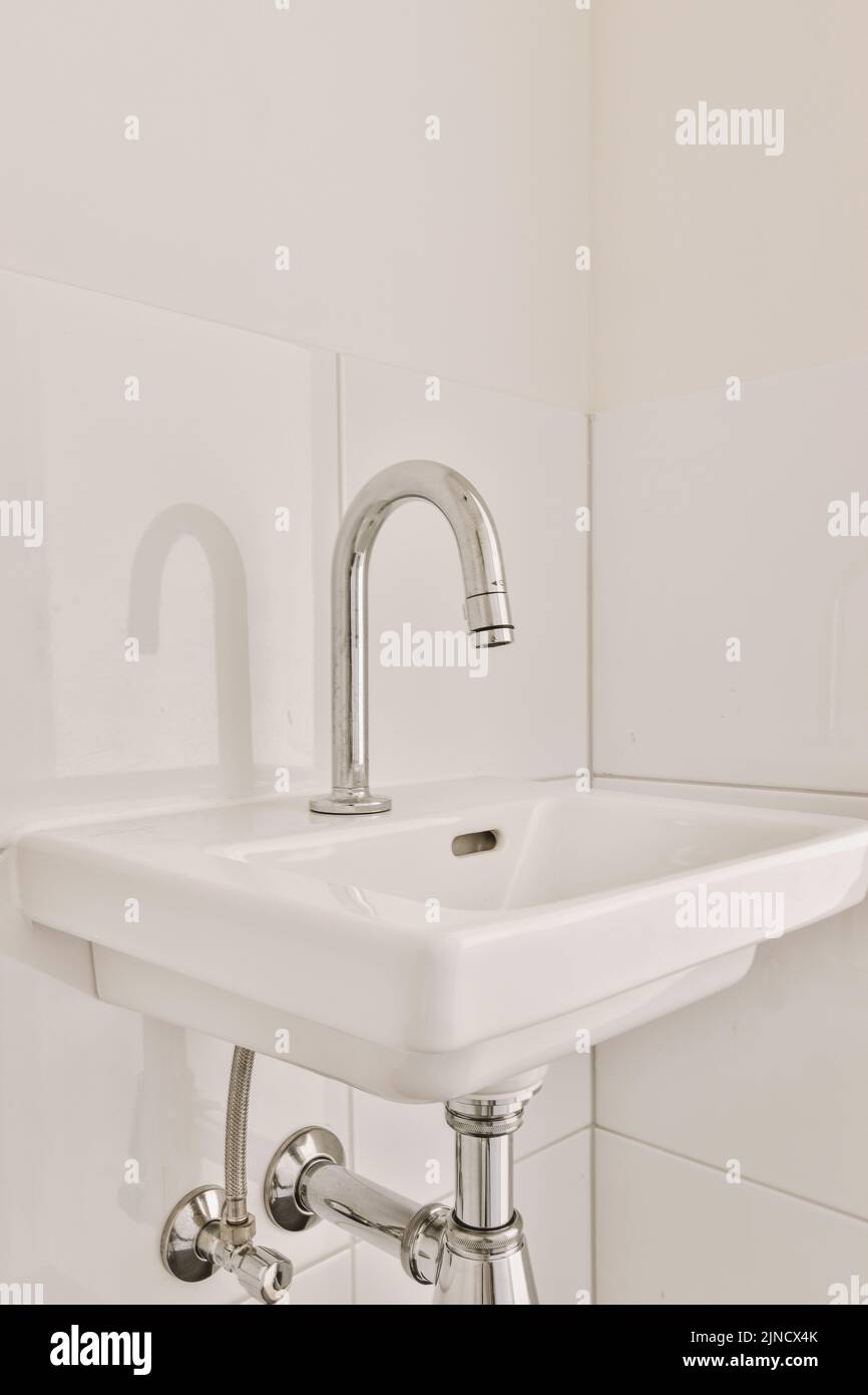 Sink with tap and liquid soap hanging on tiled wall in contemporary ...