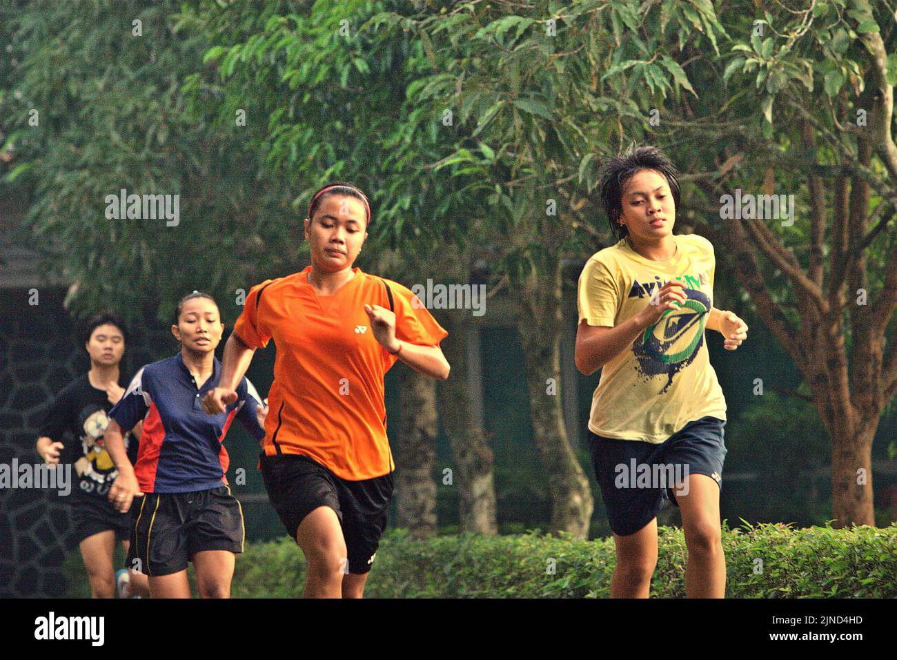 Young women badminton players are running circle a park during a ...