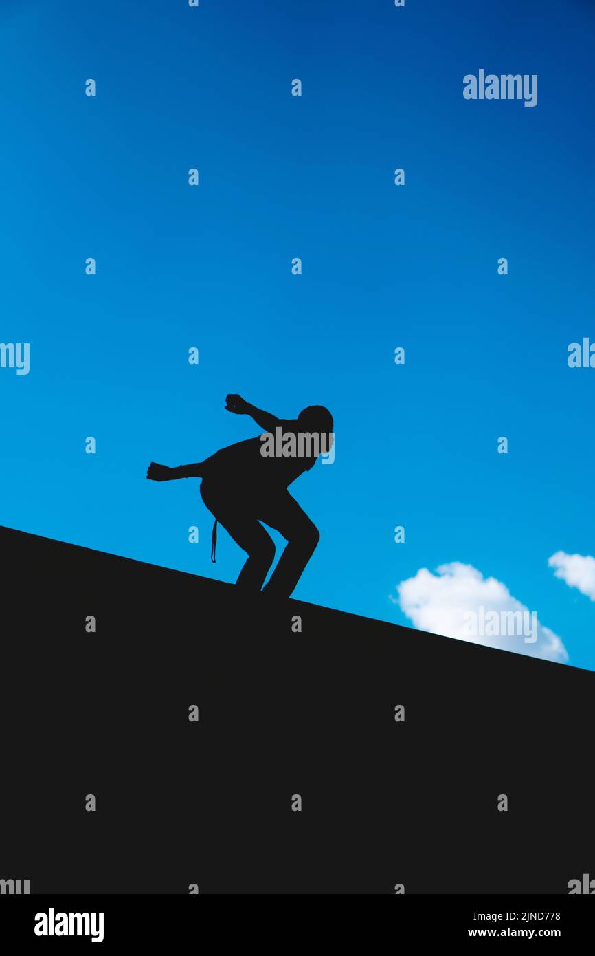 Black silhouette of a man about to do a backflip with the sky in the ...