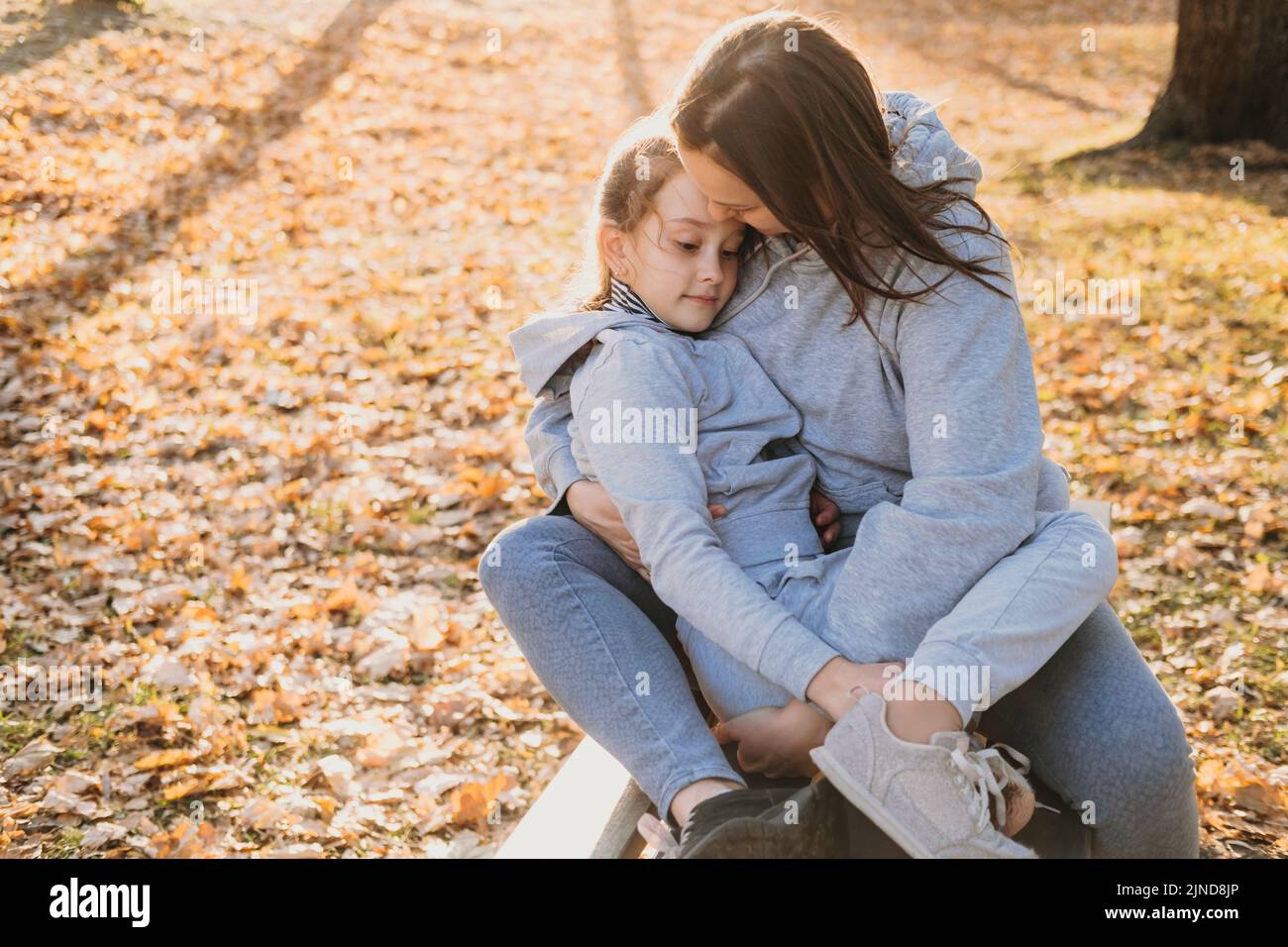 Mother and daughter spending time together in the autumn park sitting ...