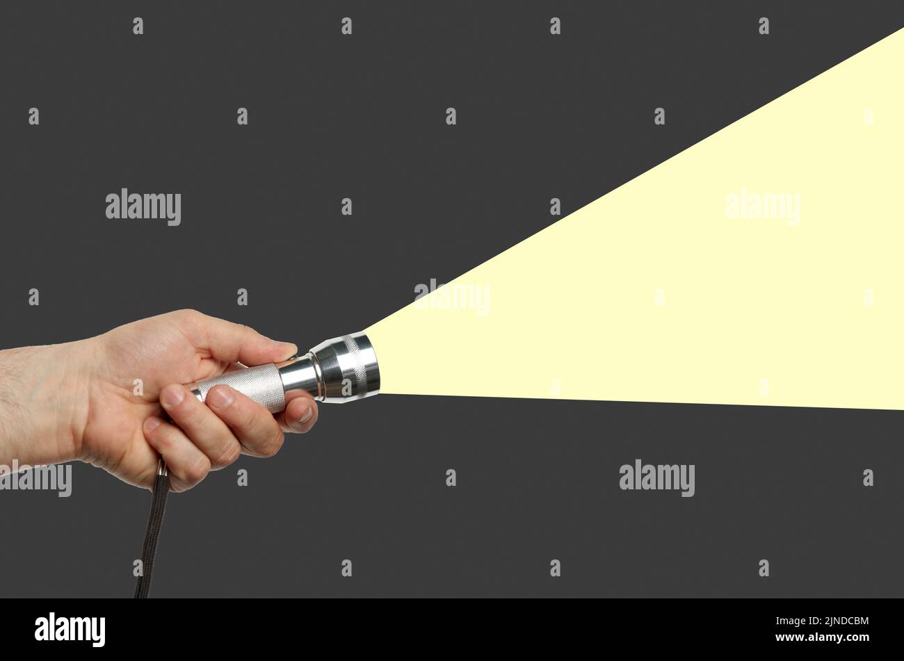 Hand with a flashlight over dark background with painted cone of yellow ...