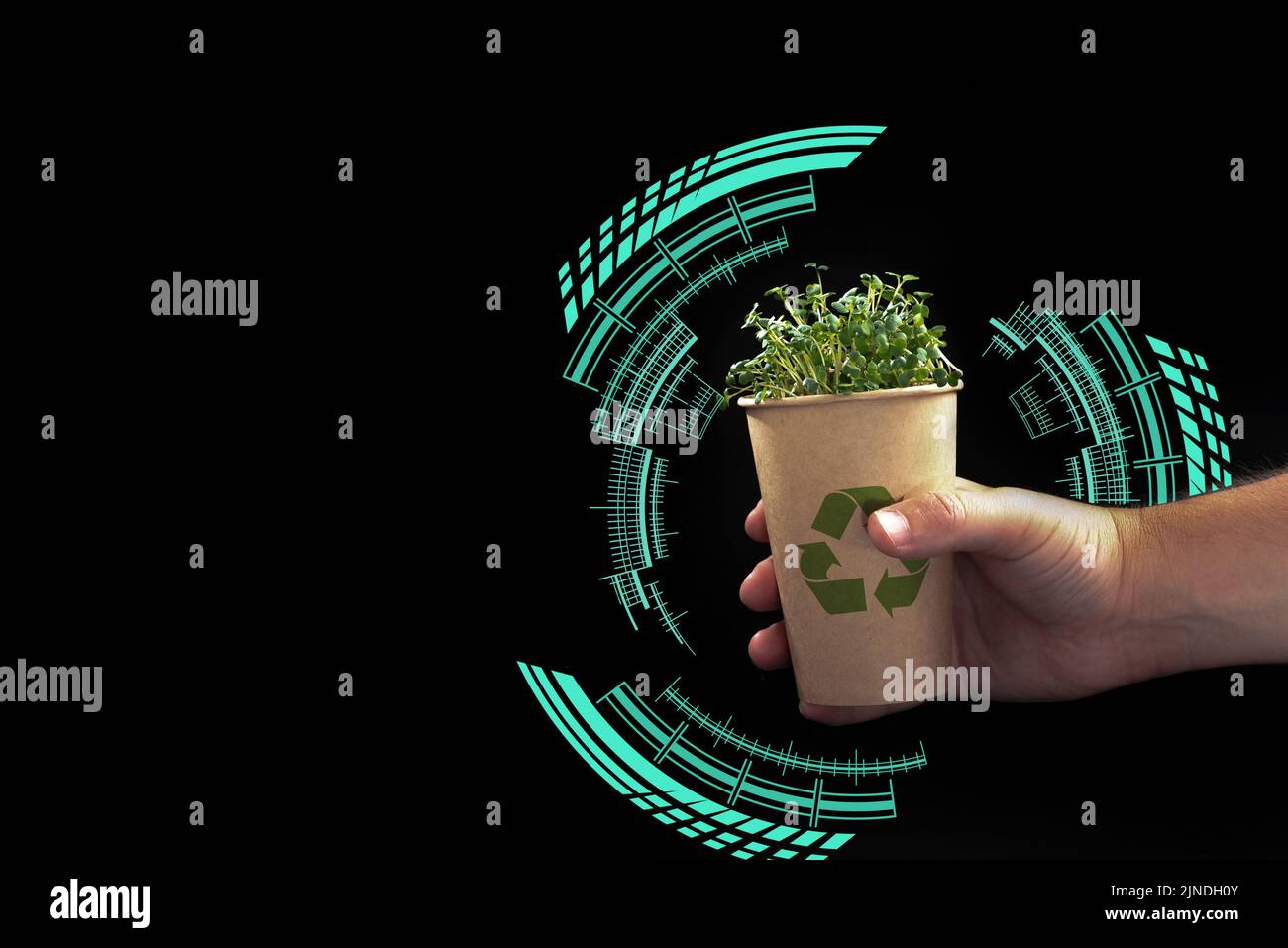 A man's hand holds an eco glass with a green plant on a black ...