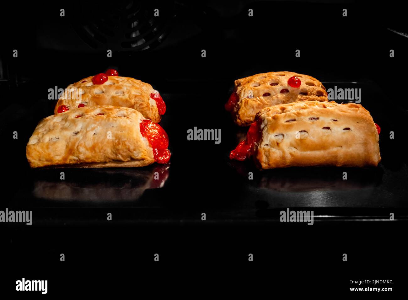 Four baked homemade buns with red strawberry jam in electric oven Stock ...