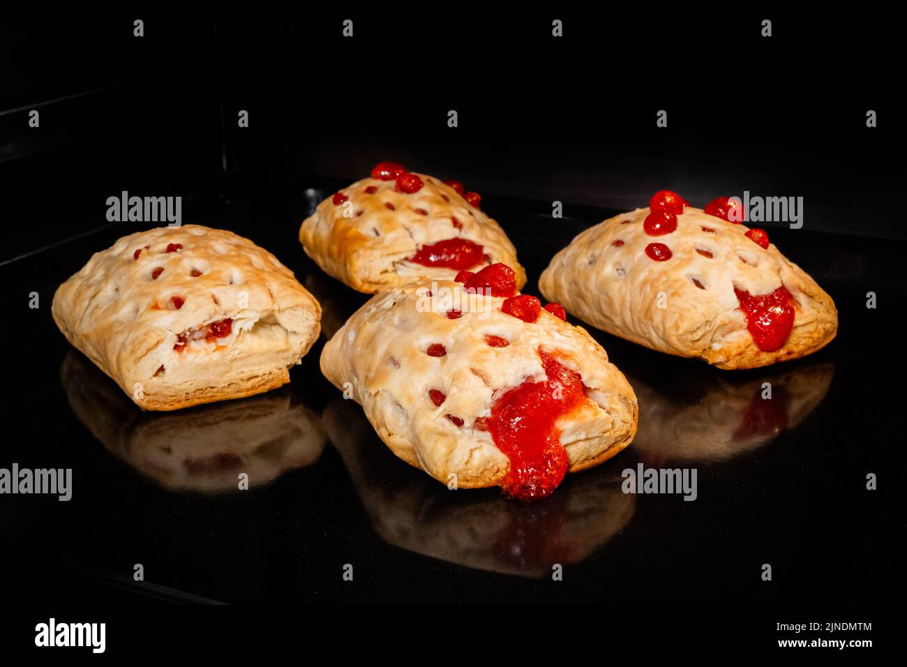 Four baked homemade buns with red strawberry jam in electric oven Stock ...