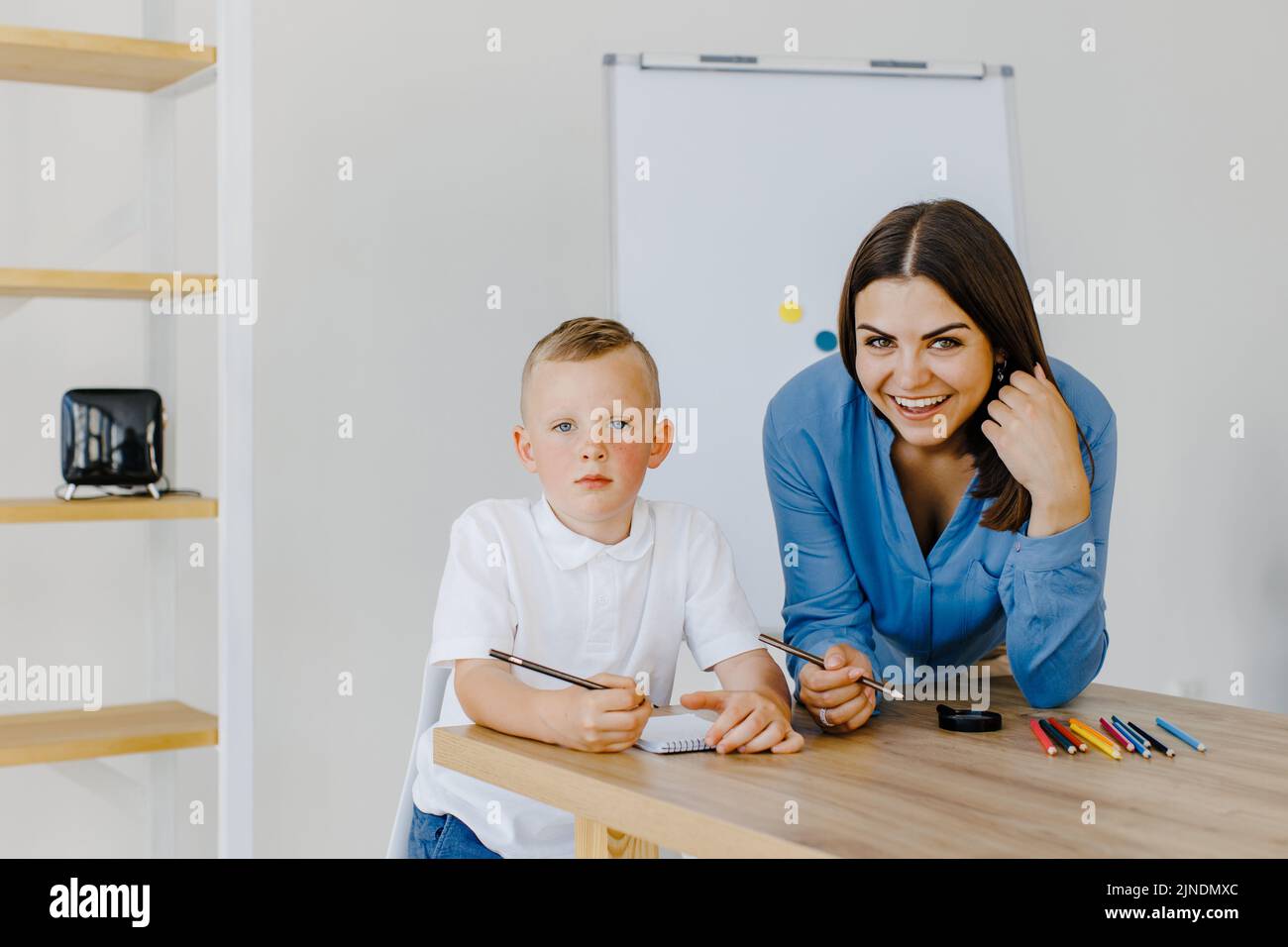Private lesson. Attentive young woman tutor teacher helping little boy ...