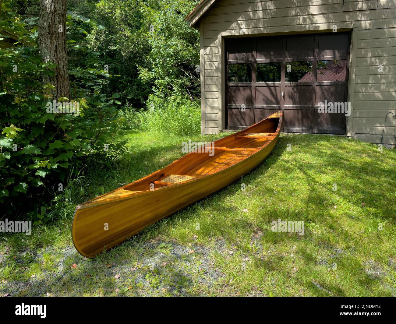 Vintage wooden canoe sitting on grass next to a cabin in the ...