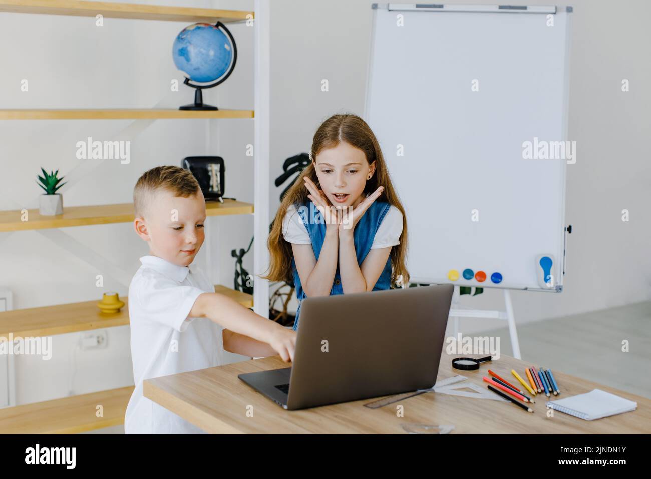 Teenage girl and first grader boy study on laptop together sitting at ...