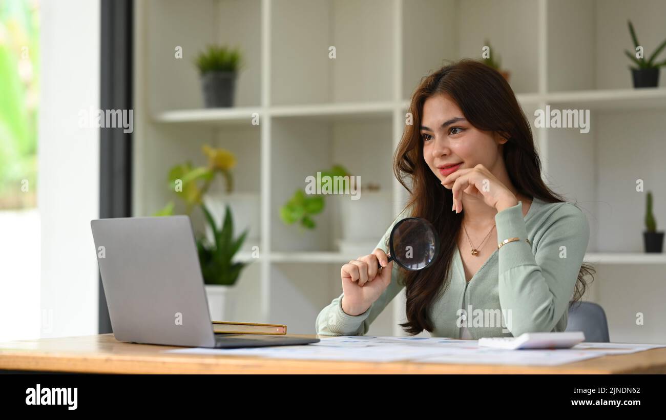 Confident young female auditor inspecting financial document with a ...