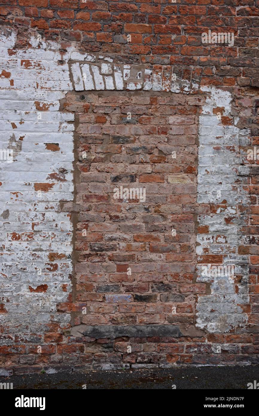 Red brick wall with a blocked up doorway and decaying white paint Stock ...