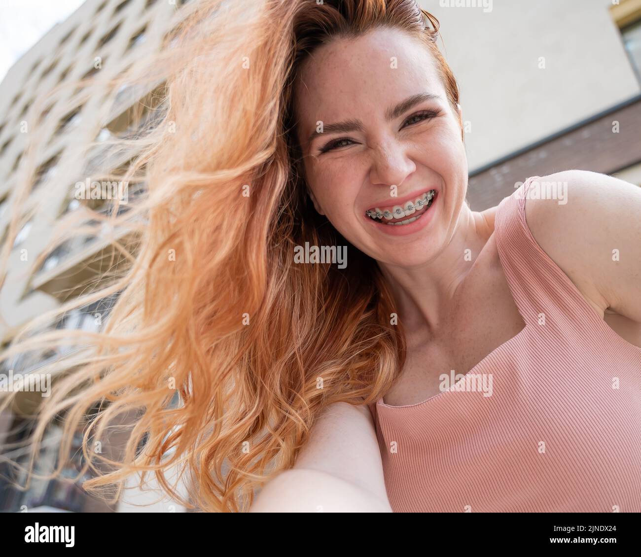 Beautiful young red-haired woman with braces on her teeth smiling in ...