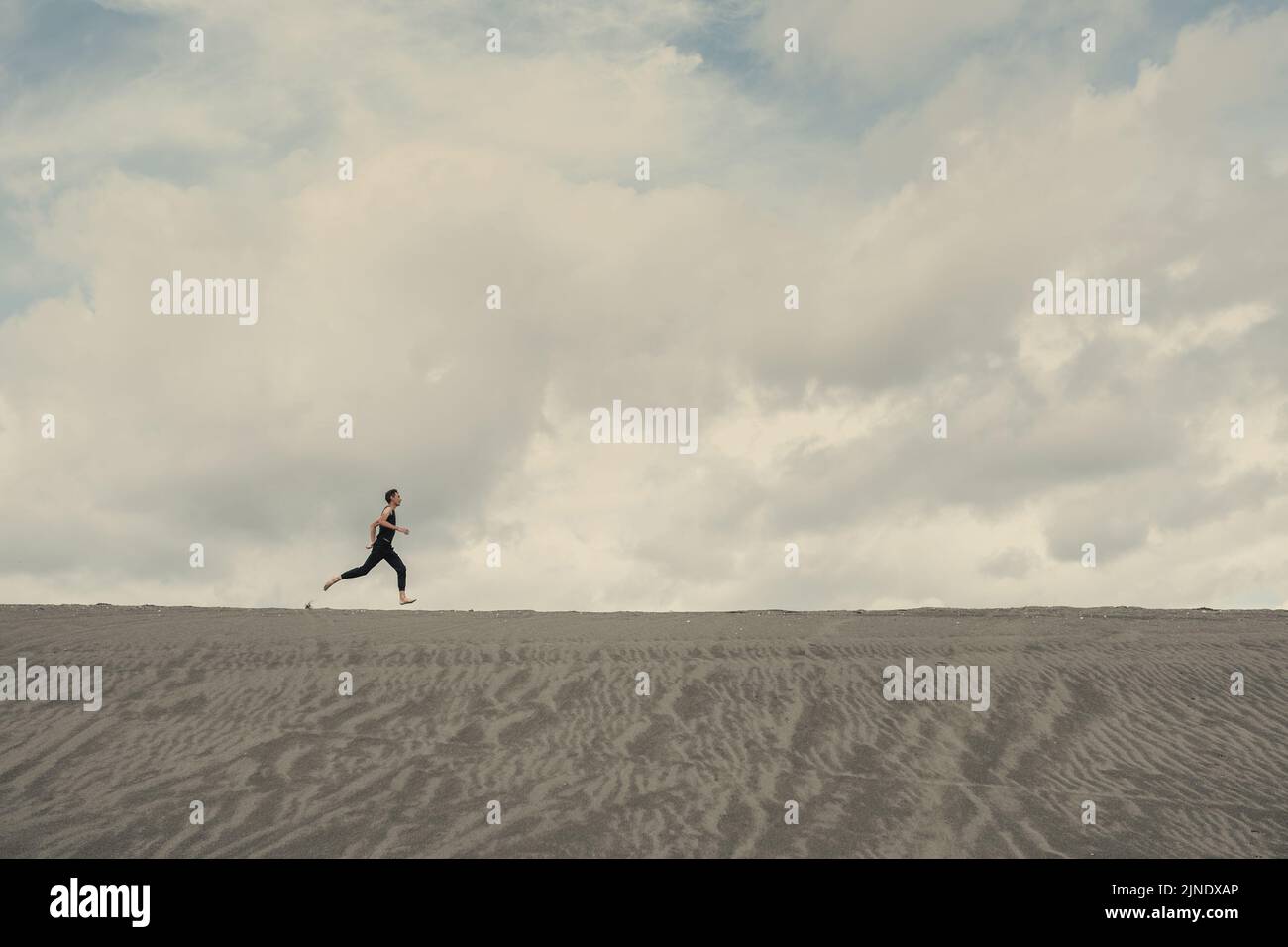 Lone man running on the sand through sandy desert Stock Photo - Alamy