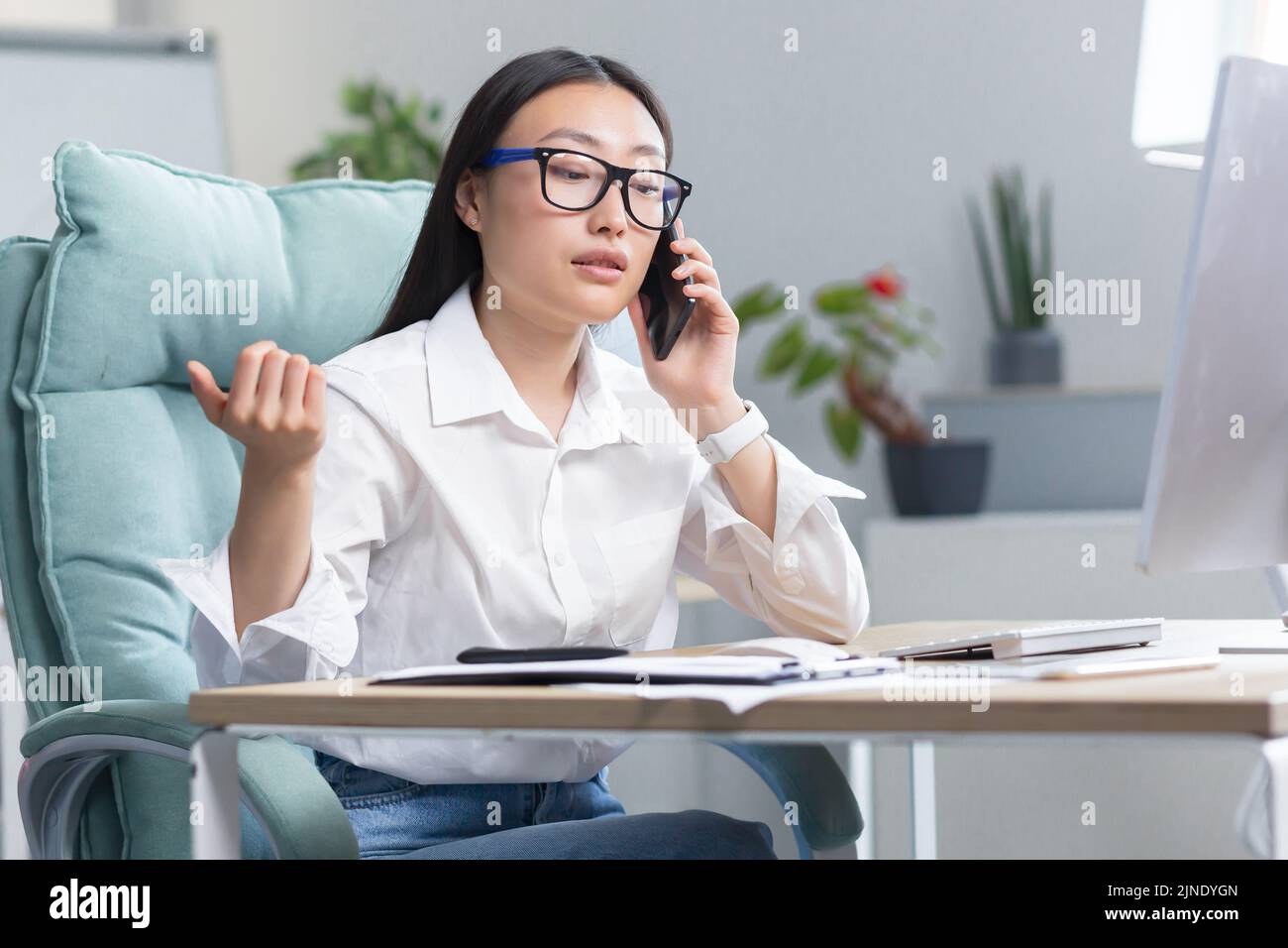 Online sales. A young beautiful Asian woman sales manager sells goods ...