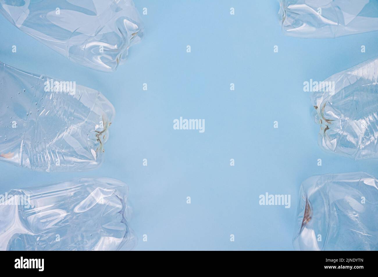 Empty rumpled used plastic bottle on blue background. Top view, copy ...