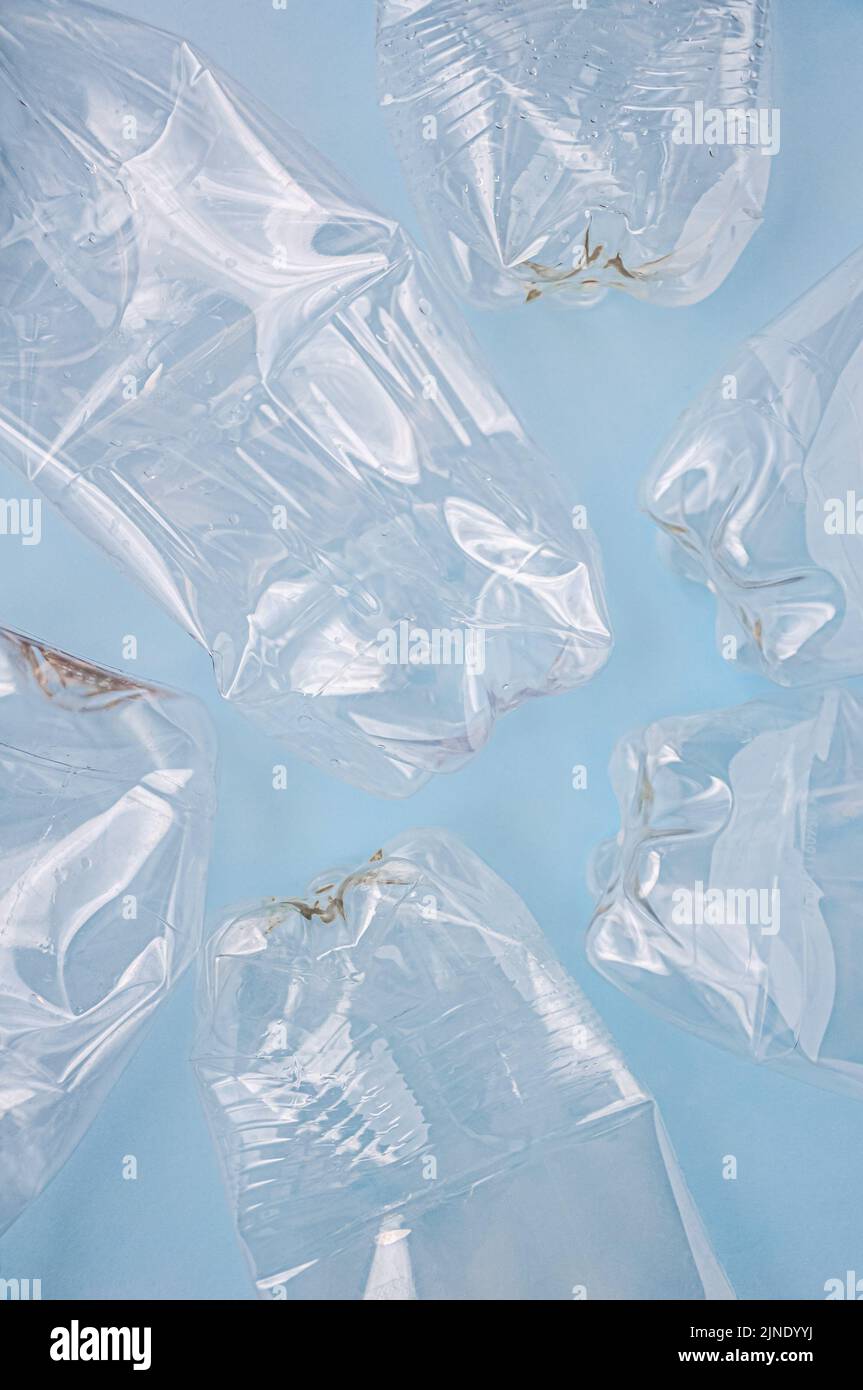 Empty rumpled used plastic bottle on blue background. Top view, copy ...