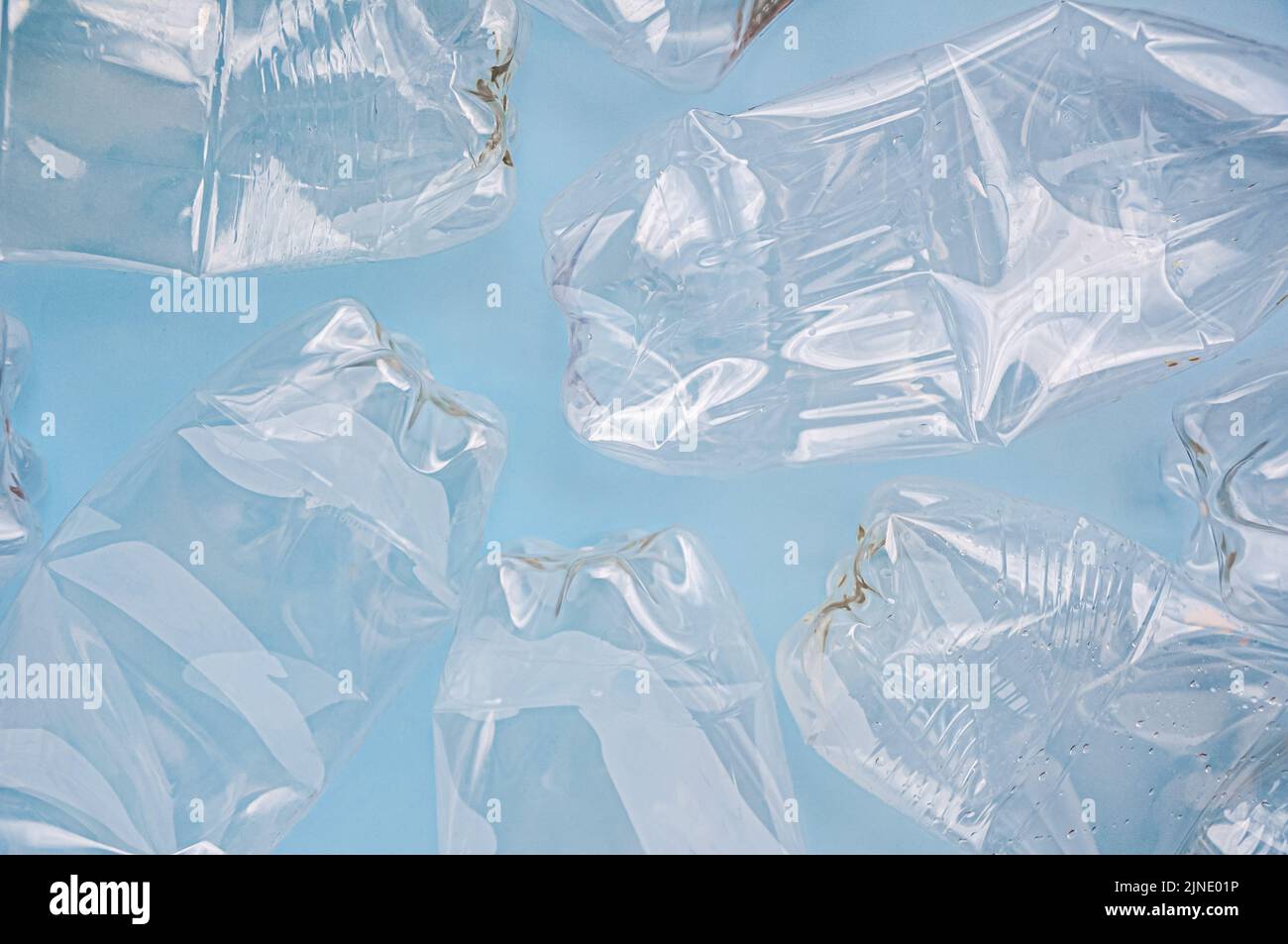 Empty rumpled used plastic bottle on blue background. Top view, copy ...