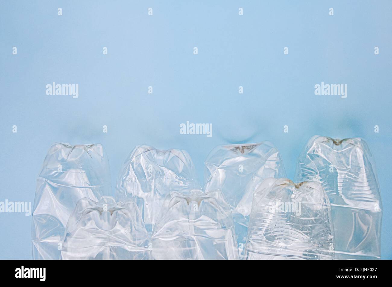 Empty rumpled used plastic bottle on blue background. Top view, copy ...