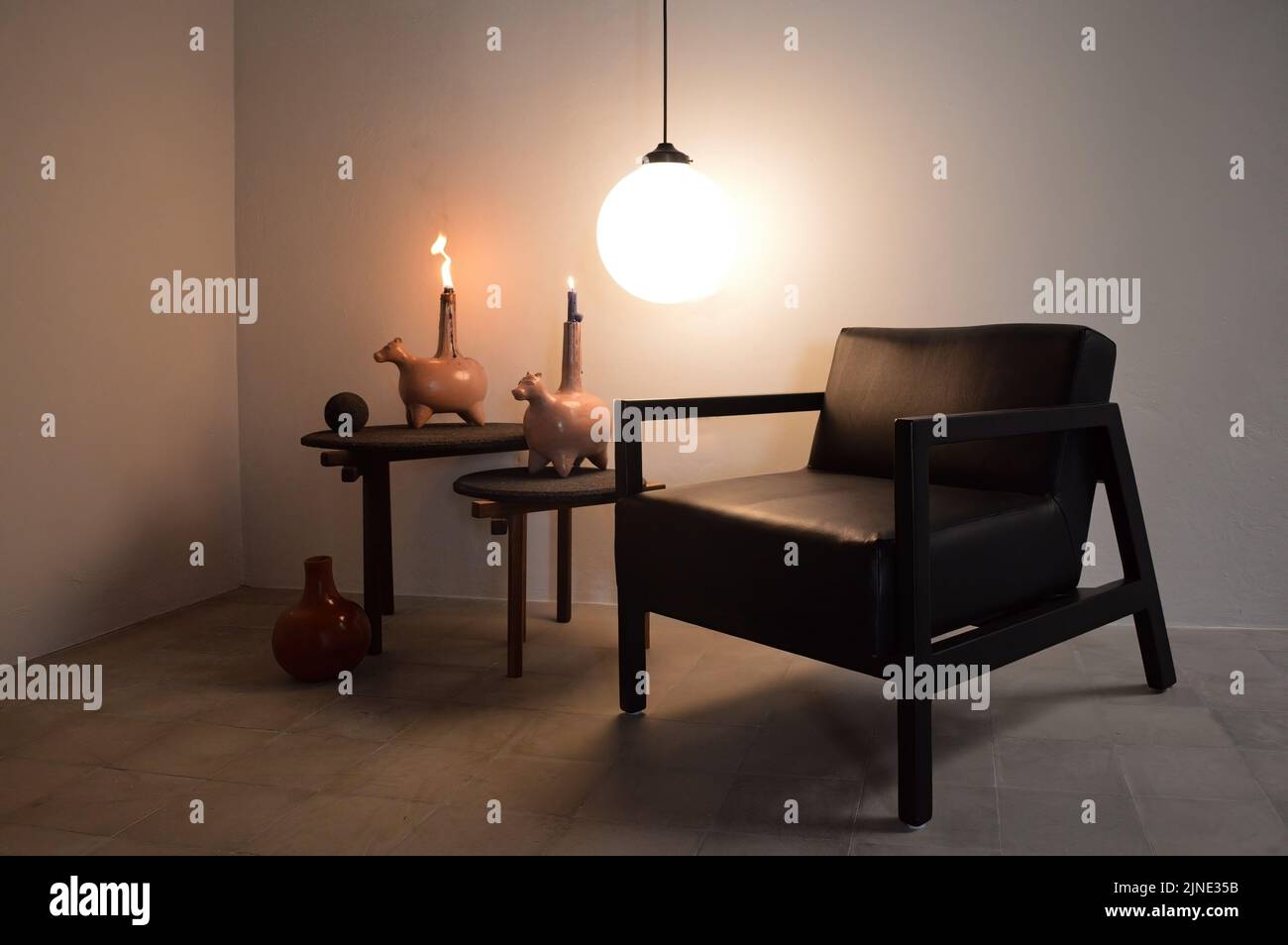 A black leather armchair by a modern small round table with burning ...