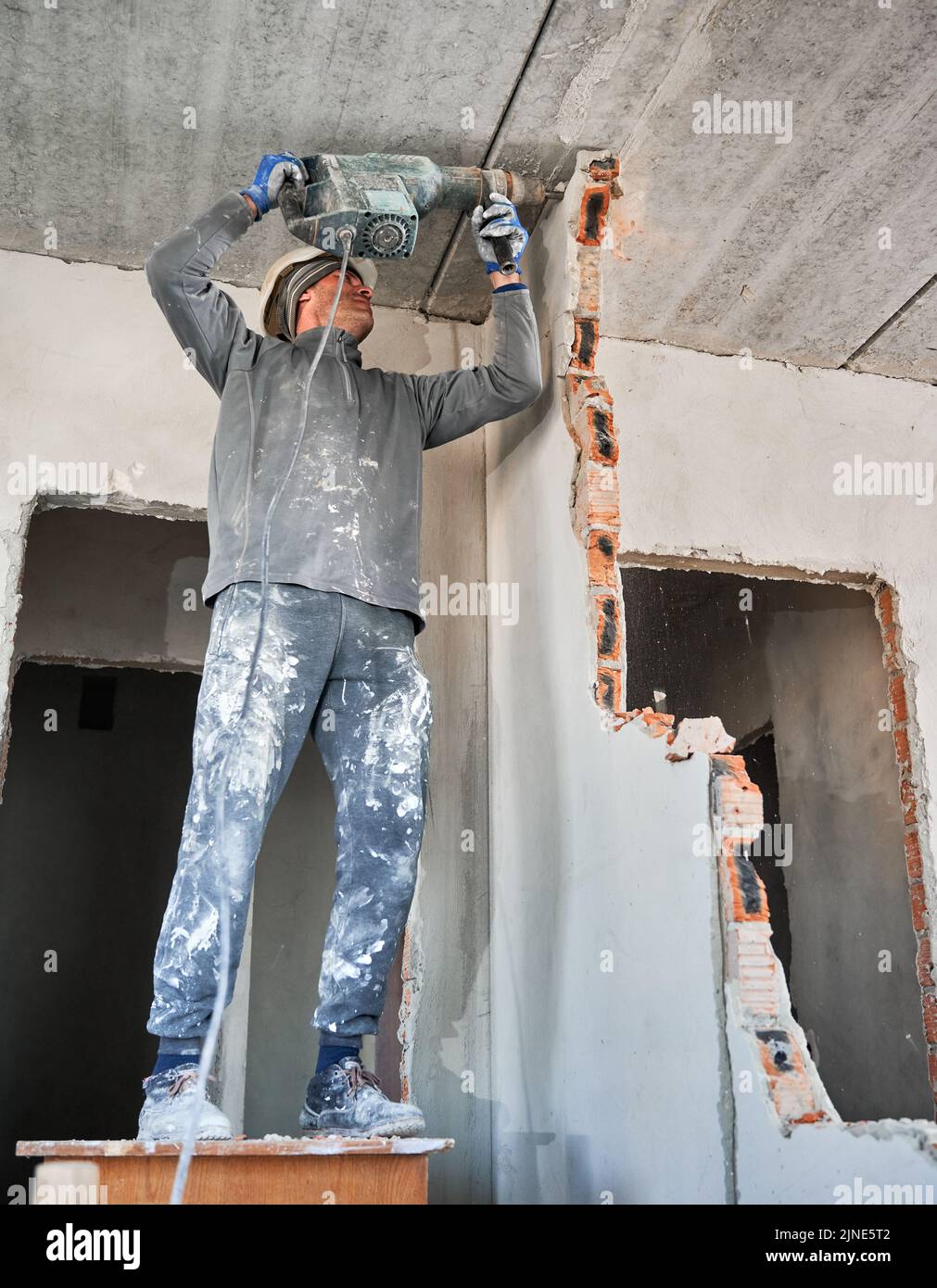 Full length of man in workwear drilling wall with hammer drill. Male ...