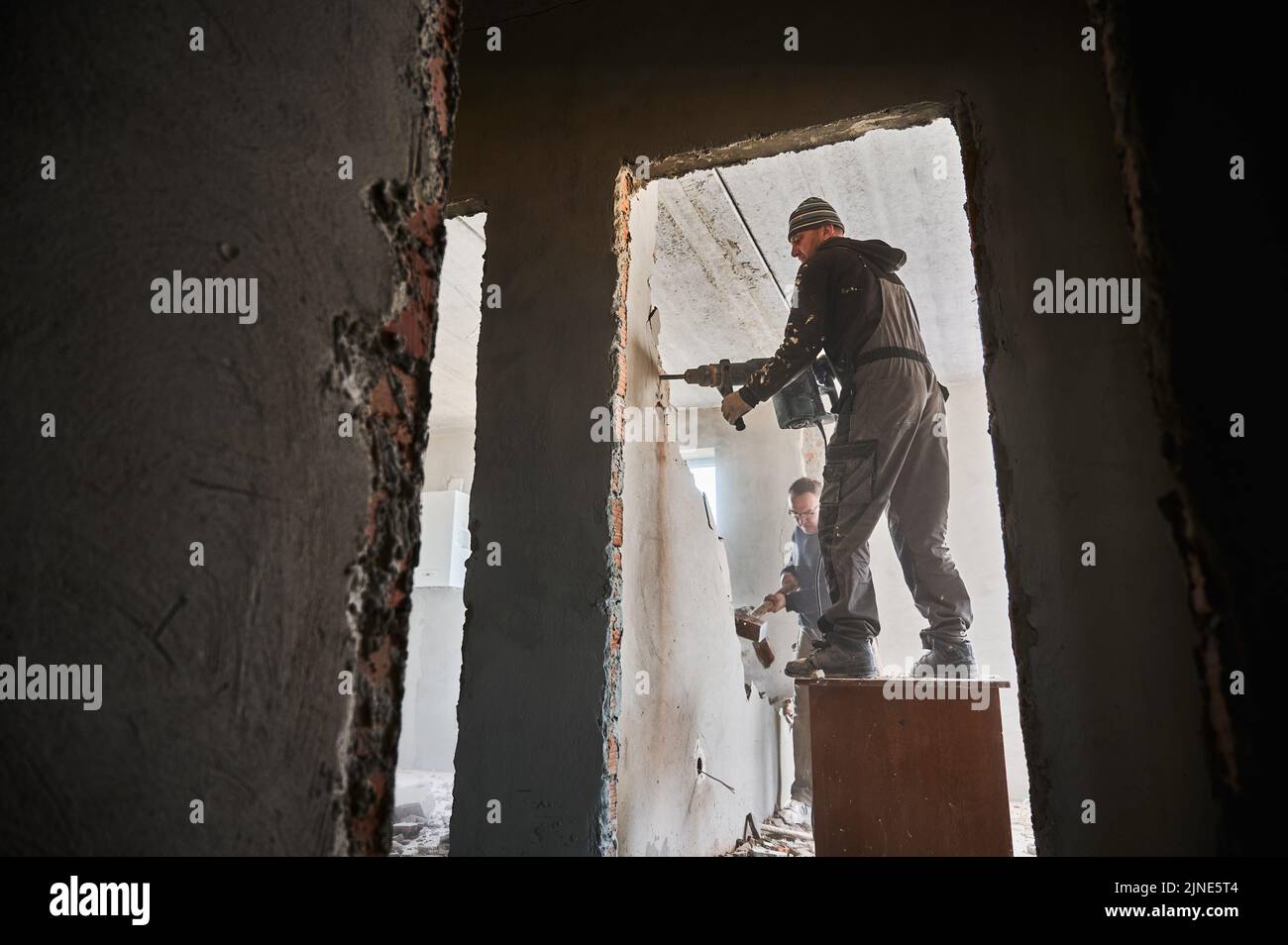 Bottom view of two builders deconstructing interior partition. One ...
