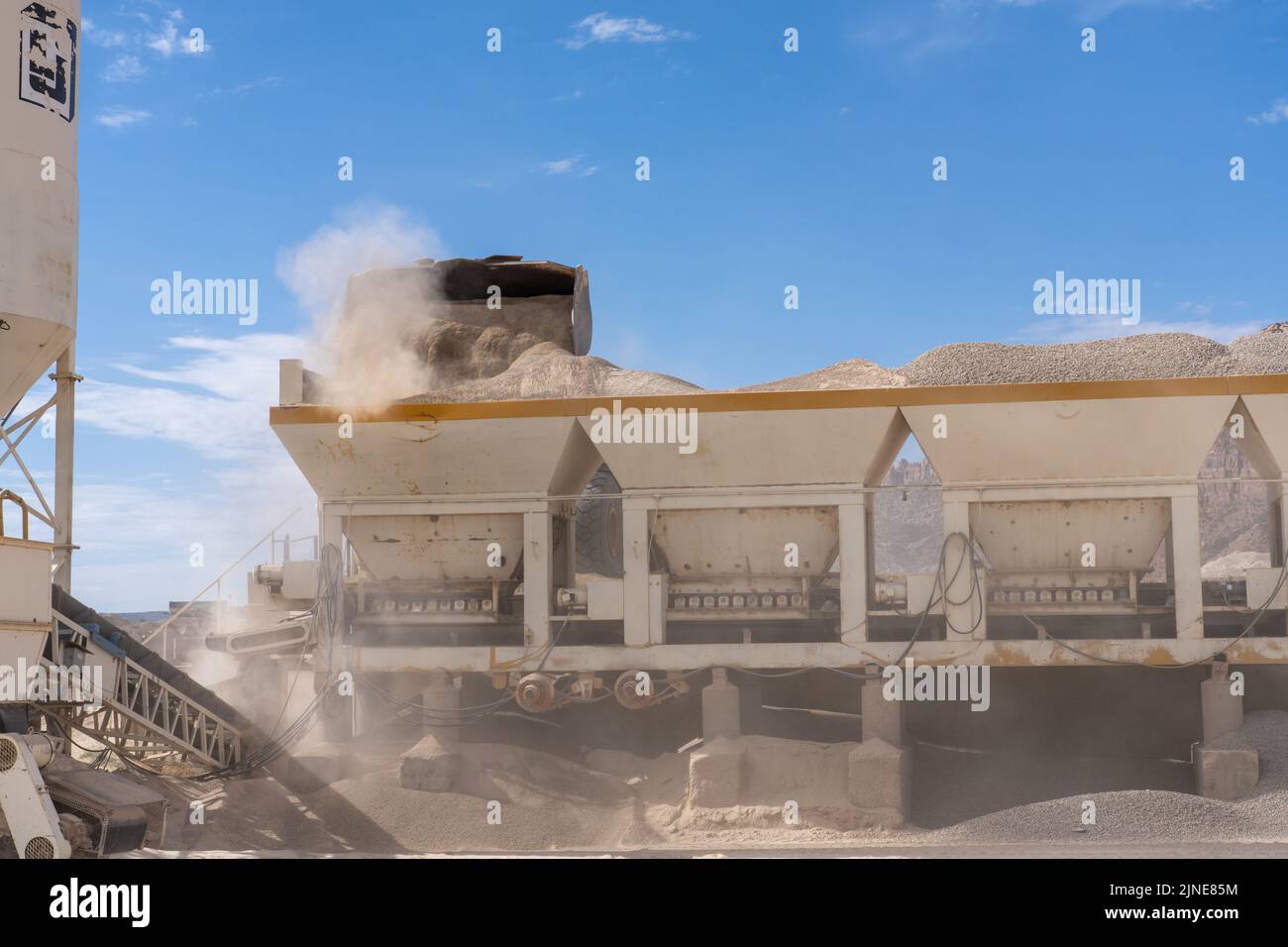 A wheel loader dumping aggregate into the cold feed bins for for the ...