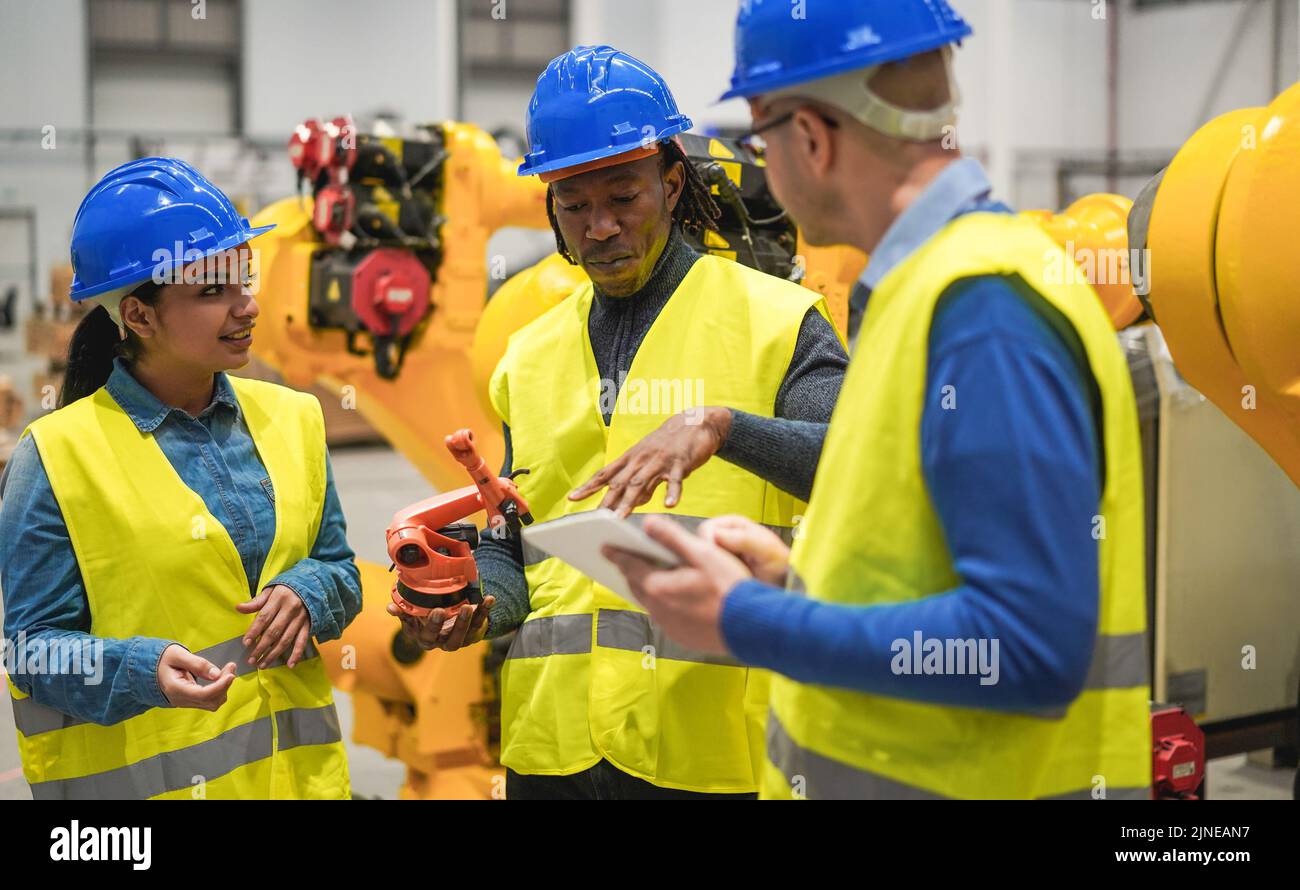 Multiracial engineers working inside robotic factory - Soft focus on ...