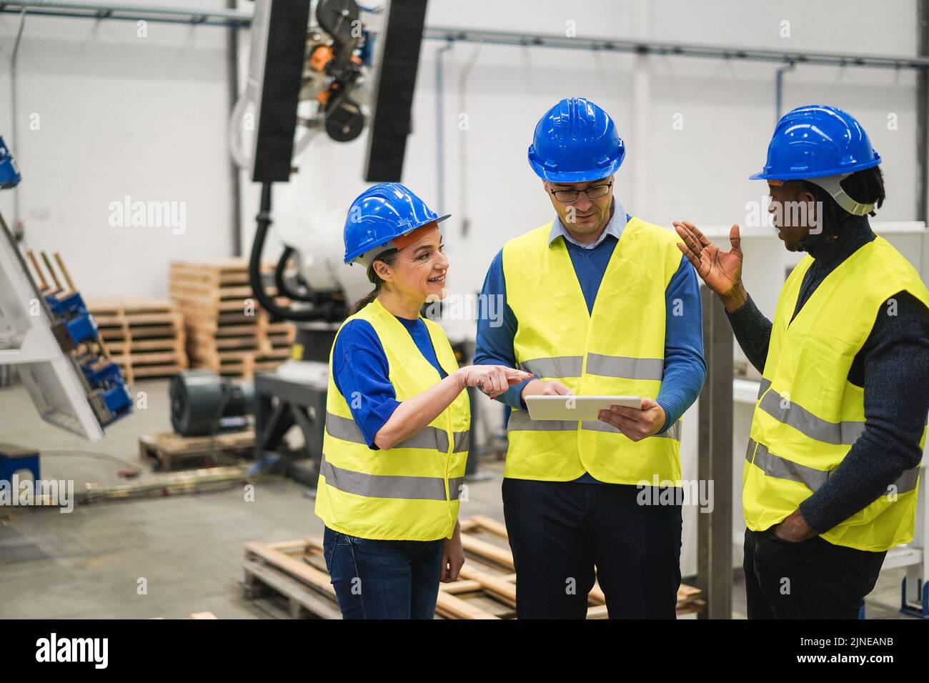 Multiracial engineers working inside robotic factory - Focus on left ...