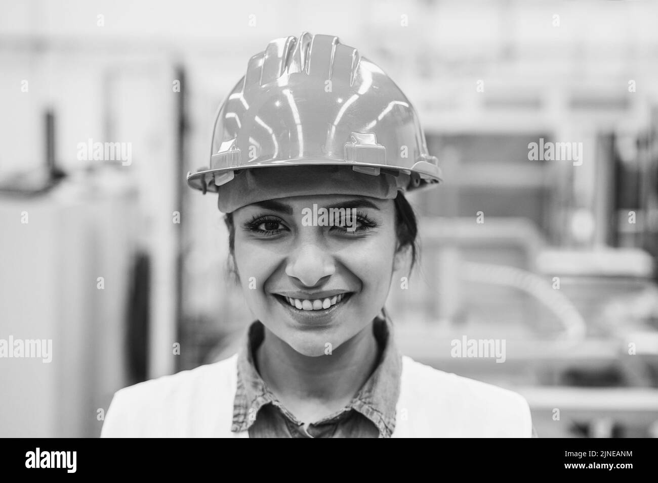 Young latin engineer working inside robotic factory - Focus on face ...
