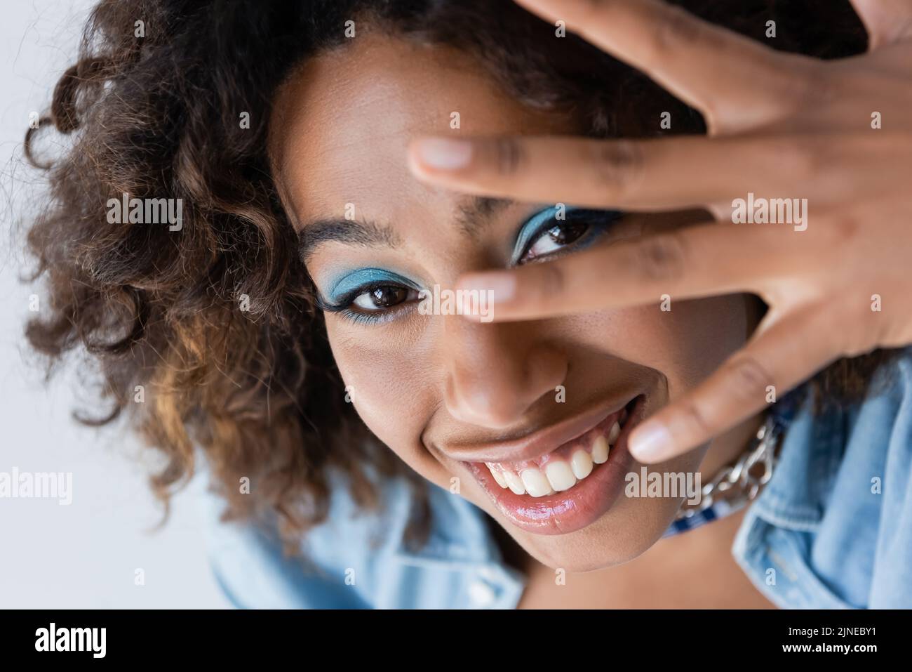 cheerful african american woman with makeup obscuring face with hand ...