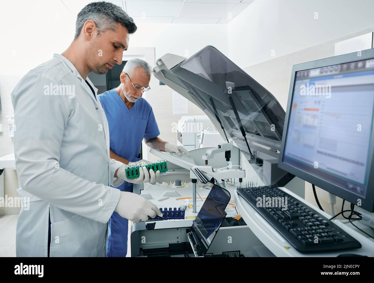 Laboratory technicians analyze blood samples near biochemical automatic ... Laboratory technicians analyze blood samples near biochemical automatic ...