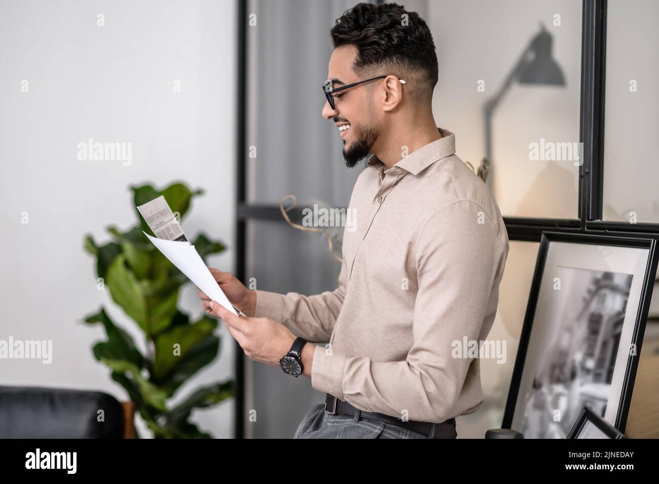 Satisfied man reading documents standing sideways to camera Stock Photo ...