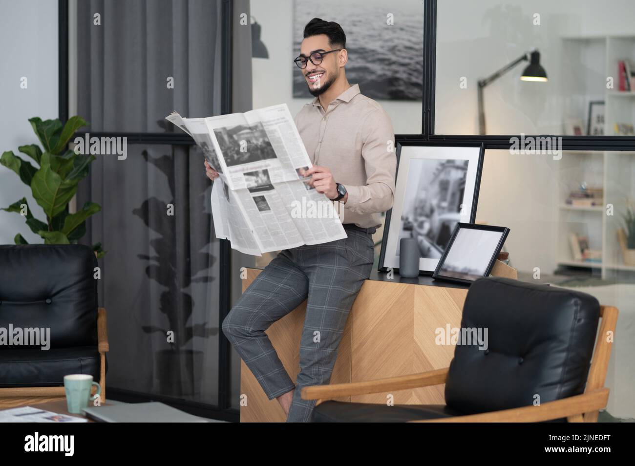 Man standing smiling reading newspaper Stock Photo - Alamy