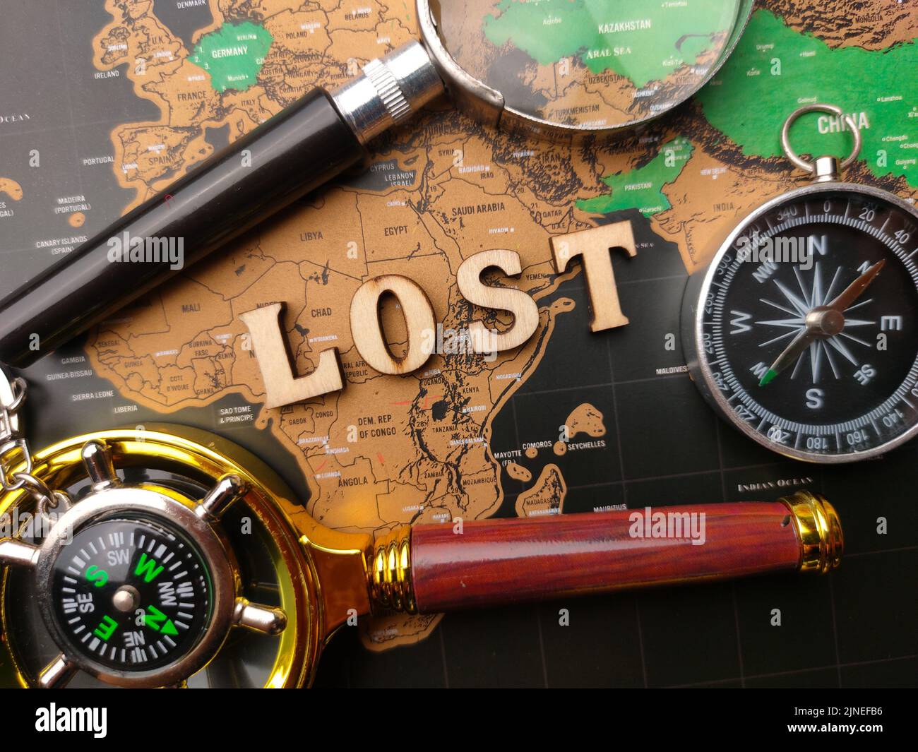 A flat lay with a magnifying glass, compass and a wooden word LOST on a ...