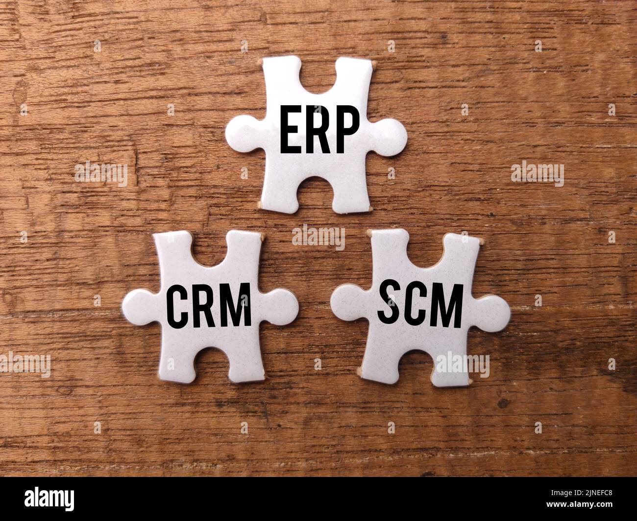 A top view of white puzzles with ERP CRM SCM on a wooden background Stock Photo - Alamy